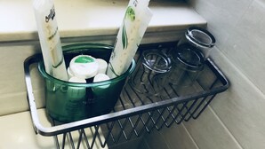 Uma bancada de cozinha com um recipiente de vidro verde contendo uma garrafa e uma embalagem, e dois potes de vidro em uma estante de metal.