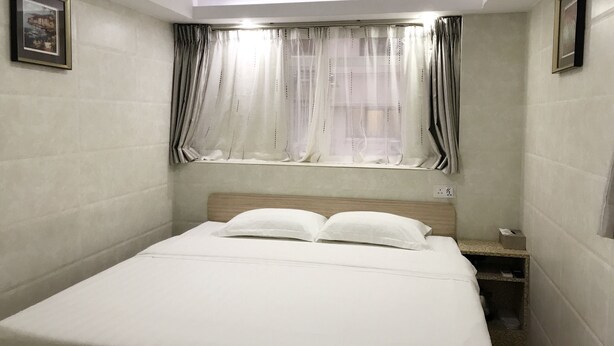 Quarto com cama, mesa de cabeceira, janela com cortinas e luminária no teto.