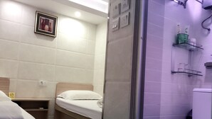 Quarto de hotel com cama, mesa de cabeceira, banheiro com vaso sanitário e chuveiro.