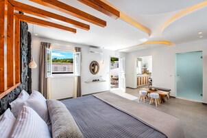 Quarto moderno com uma cama grande, teto de madeira e vista para o exterior.
