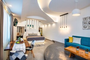 Uma sala de estar moderna com um sofá, uma mesa de jantar com uma fruteira e uma cama com vista para a área de refeições.