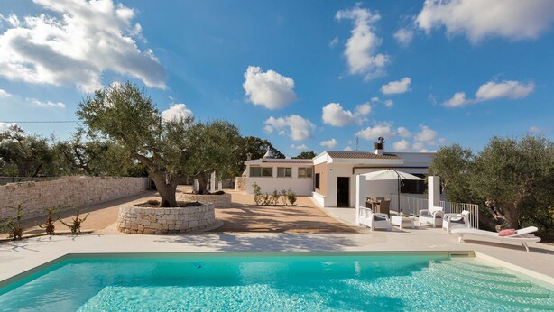 Uma villa moderna com piscina, área de estar externa e um muro de pedra.