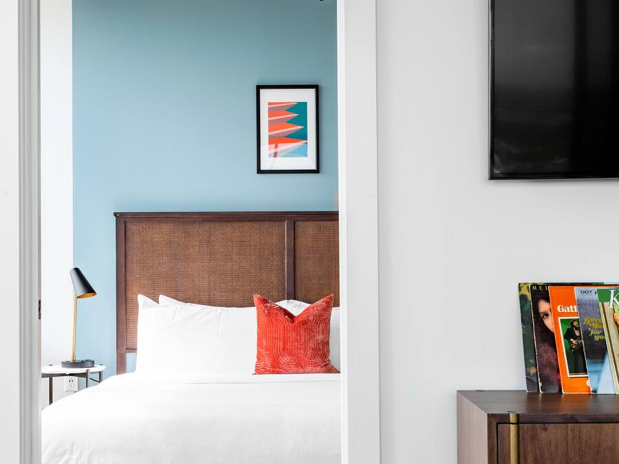 Quarto com cama, ventilador de teto, mesa de cabeceira, abajur, quadro emoldurado, televisão e armário de madeira.