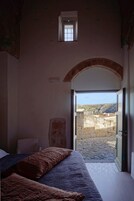 Quarto com cama, janela e porta aberta para um pátio.