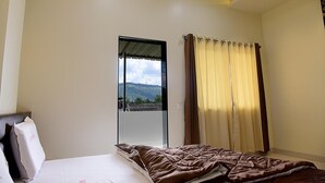 Quarto com cama, janela com vista para montanha e cortinas.