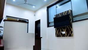 Quarto moderno com ventoinha no teto, iluminação embutida, janela com persianas e TV fixada na parede.