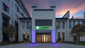 Entrada de hotel com design moderno, fachada de vidro e placa da Holiday Inn Express.
