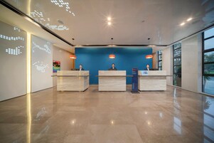 Uma área de recepção com três balcões, uma parede texturizada azul e um design de teto moderno.