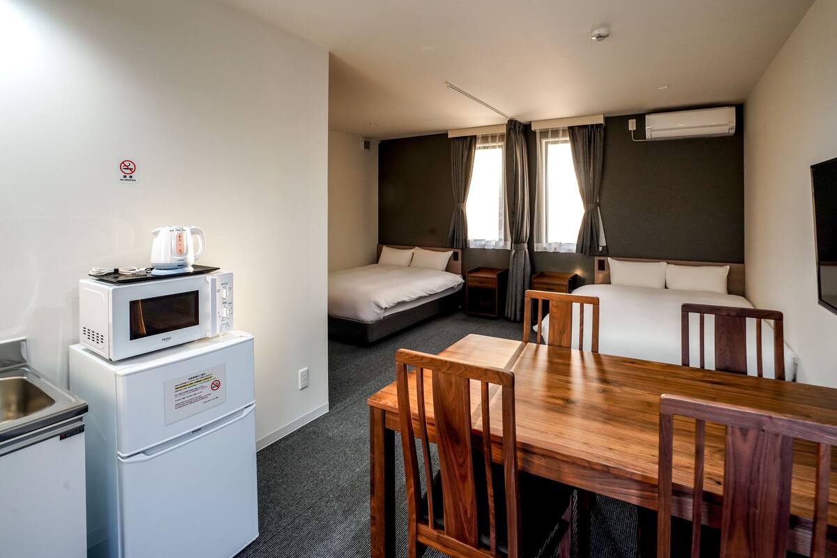 Quarto de hotel compacto com cozinha compacta, cama, sofá e área de refeições.