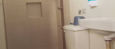 Casa de banho pequena com sanita, lavatório e chuveiro.
