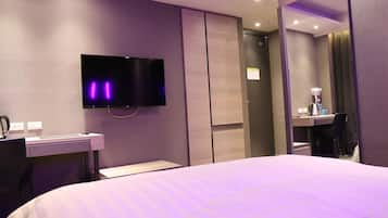 Quarto de hotel moderno com uma cama grande, televisão de tela plana na parede, uma escrivaninha com cadeira e um espelho.