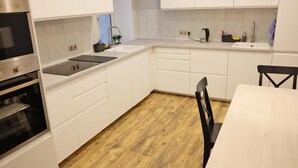 Uma cozinha moderna com armários brancos, piso de madeira e uma cadeira preta.