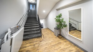 Escada moderna com piso de madeira, corrimão e espelho fixado na parede.