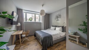 Quarto moderno com cama, escrivaninha, cadeira e uma grande janela.
