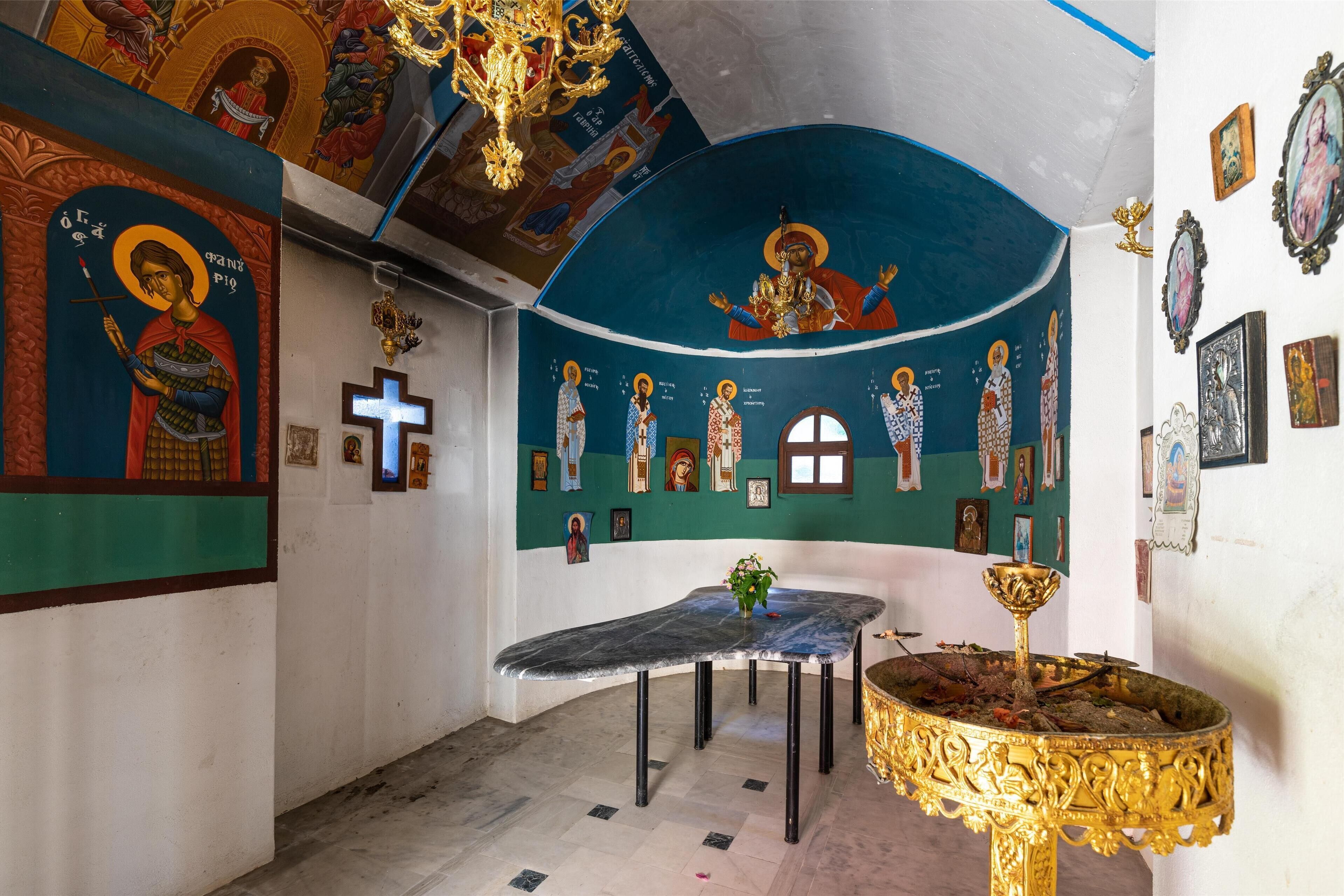 Interior de igreja com ícones religiosos, altar de mármore e candelabro dourado.
