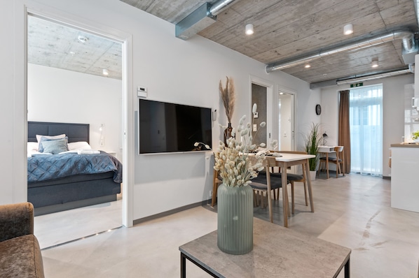Quarto de hotel moderno com cama, área de refeições e sala de estar.