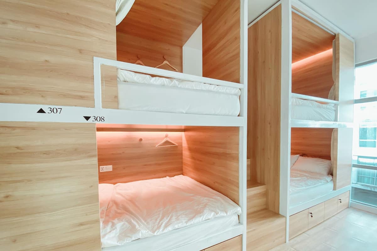 Quarto com beliches, paredes de madeira e roupa de cama branca.