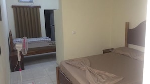 Quarto com cama, ventilador e janela com cortinas.