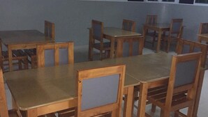 Um quarto com várias mesas e cadeiras de madeira dispostas em padrão de grade.