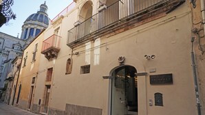 Um edifício histórico com uma cúpula imponente e uma varanda com grades vermelhas.