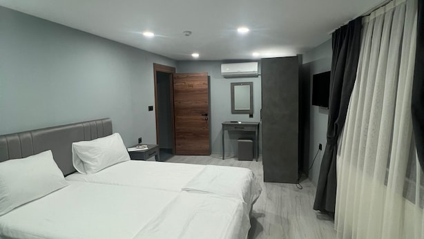 Quarto de hotel moderno com uma cama grande, uma escrivaninha, um espelho e uma televisão.