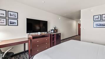Quarto de hotel com cama, escrivaninha, cômoda, televisão e micro-ondas.