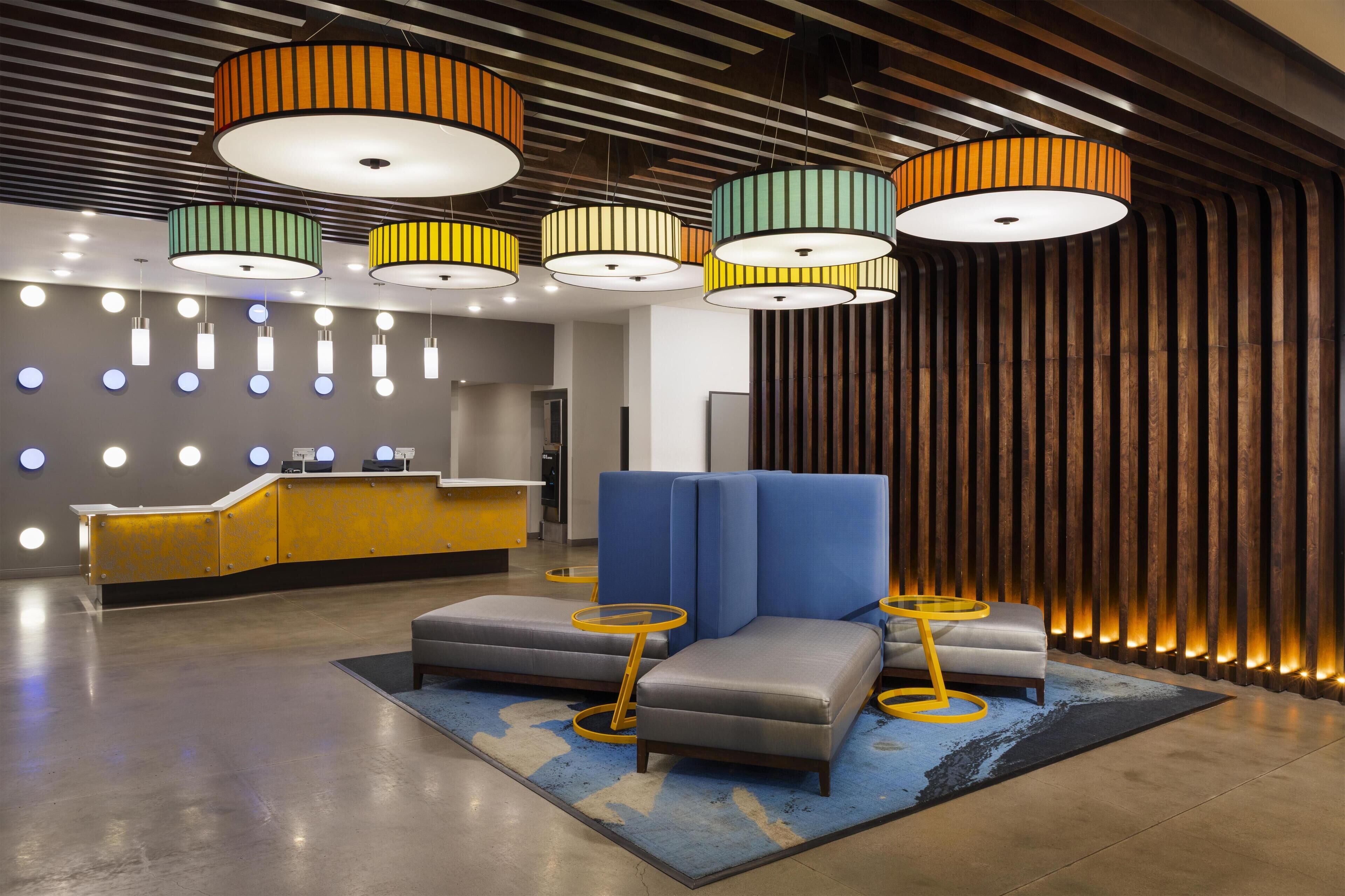 Um hall moderno com balcão de recepção, área de estar e iluminação decorativa.
