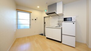 Uma cozinha compacta com micro-ondas, pia e exaustor de aço inoxidável.