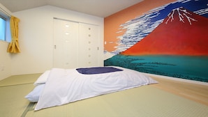 Quarto com cama em esteira de tatame, porta deslizante e painel com montanhas e oceano.