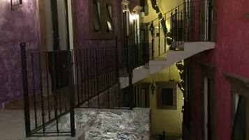 Uma passagem estreita com uma escadaria de pedra que leva a um edifício com fachada rosa e uma varanda.