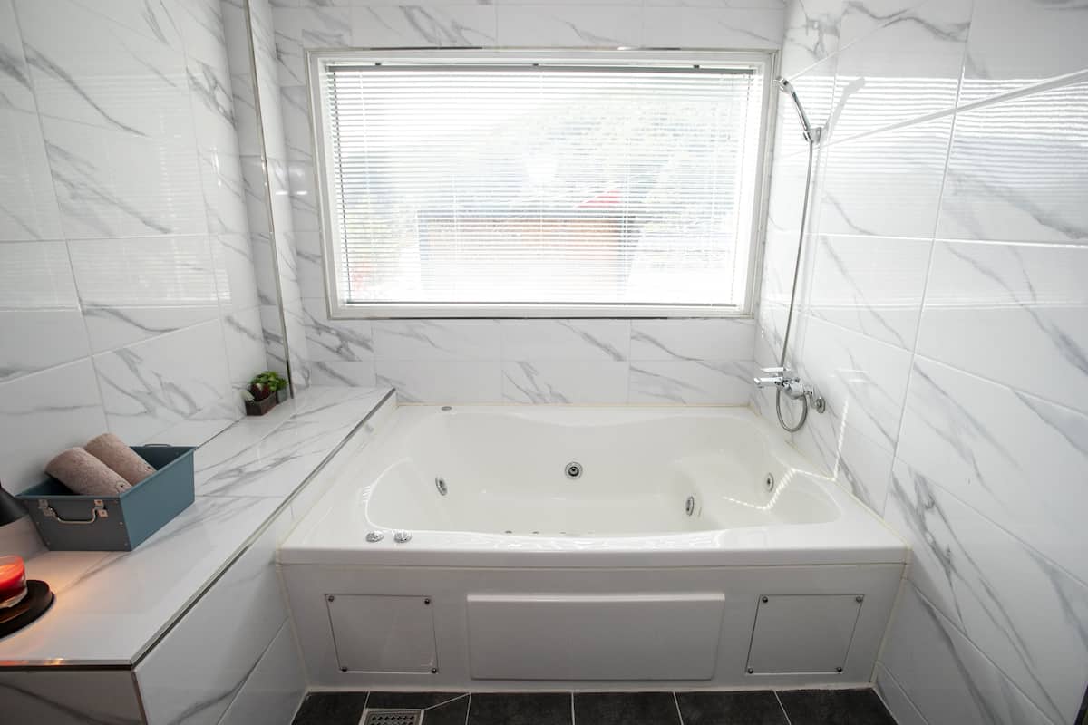 Um banheiro moderno com uma banheira grande, uma janela e um porta-toalhas.