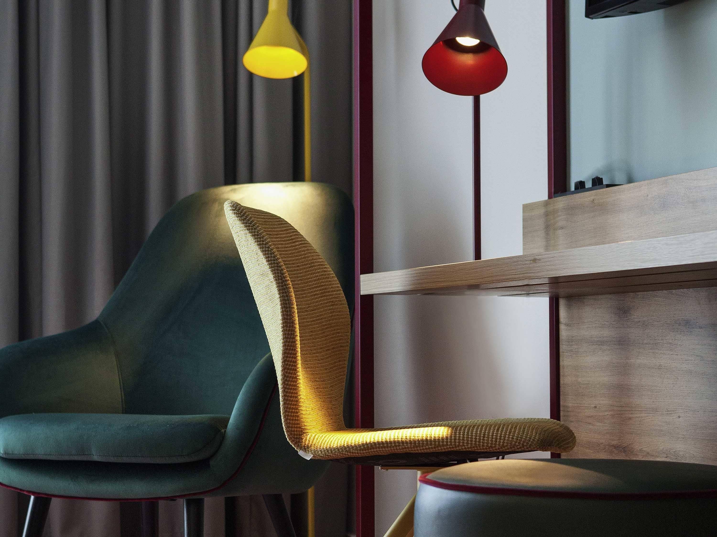 Uma cadeira moderna com design único, uma prateleira de madeira e uma luminária pendente vermelha.