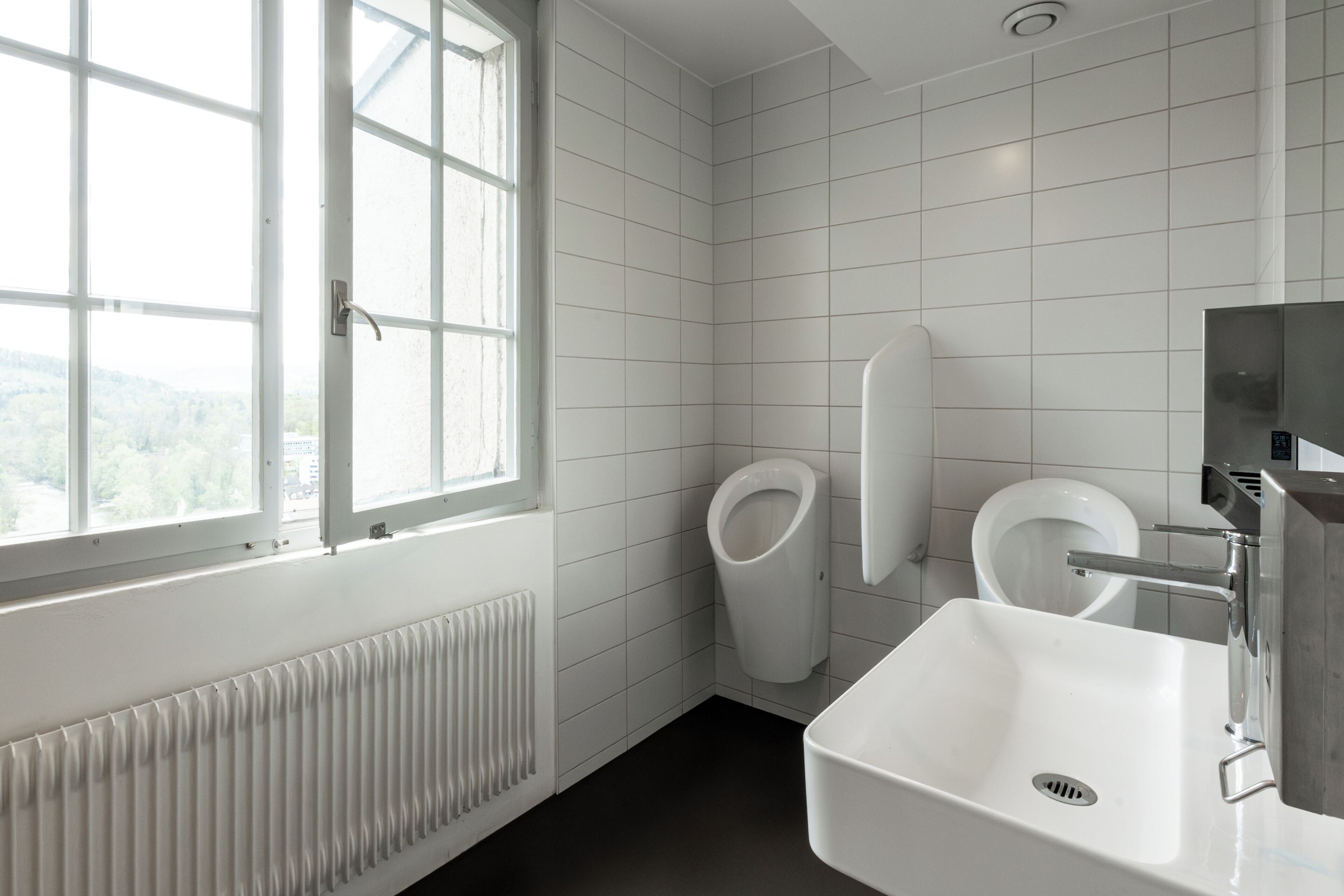 Uma casa de banho moderna com janela, sanita, lavatório e loiça sanitária.