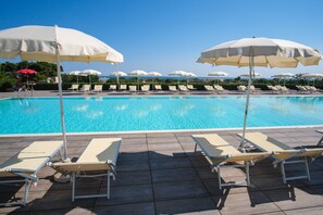Uma área de piscina com espreguiçadeiras e guarda-sóis.
