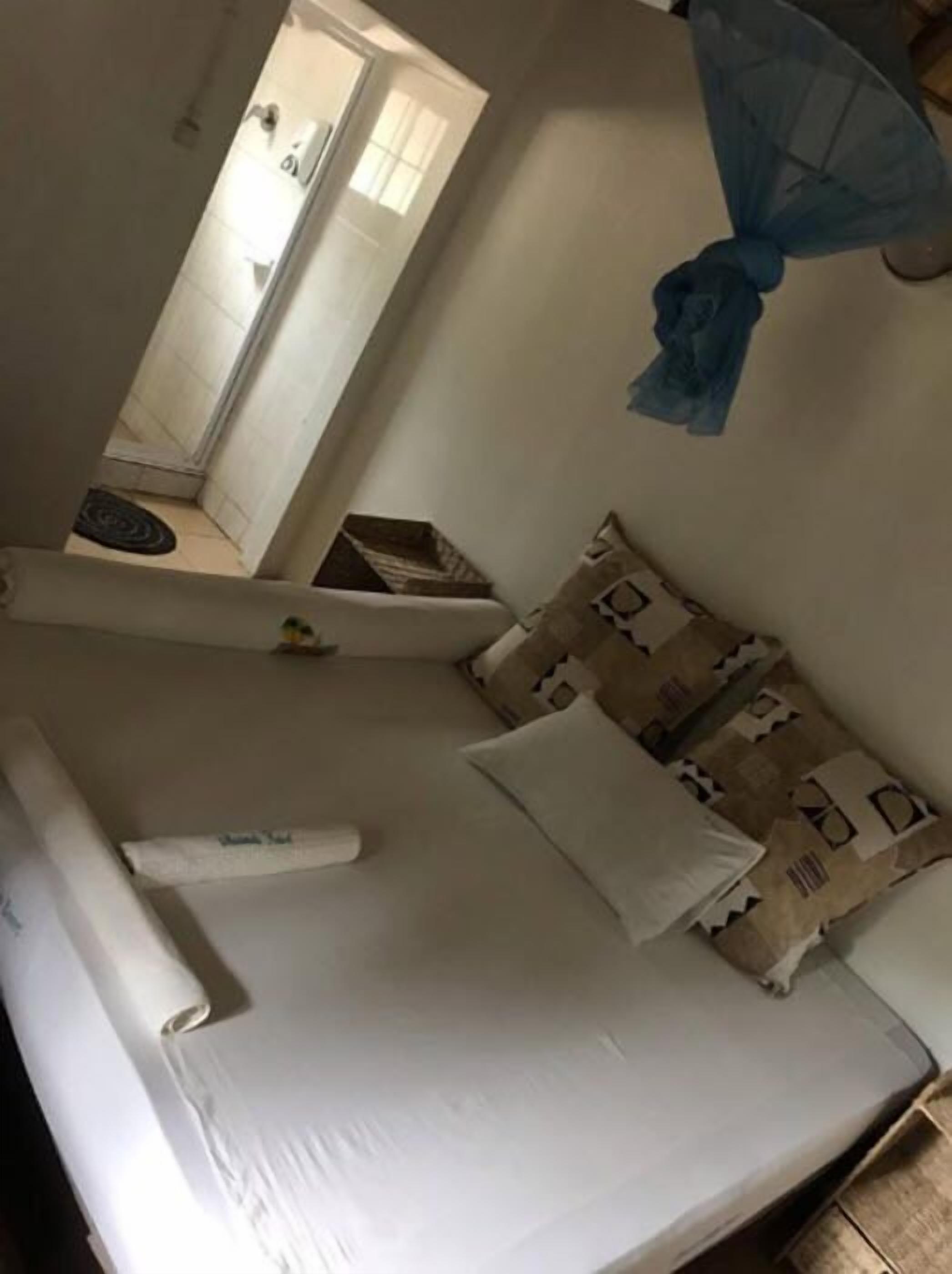 Quarto com cama, almofadas, mesa de cabeceira e janela.