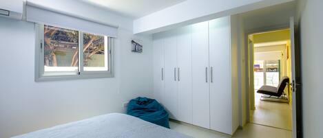 Quarto com cama, janela, guarda-roupa e um puff.