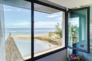 Vista de uma varanda com vista para uma praia, sob um céu limpo.