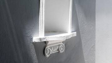 Paredes brancas com um arco de metal decorativo e uma pequena janela.