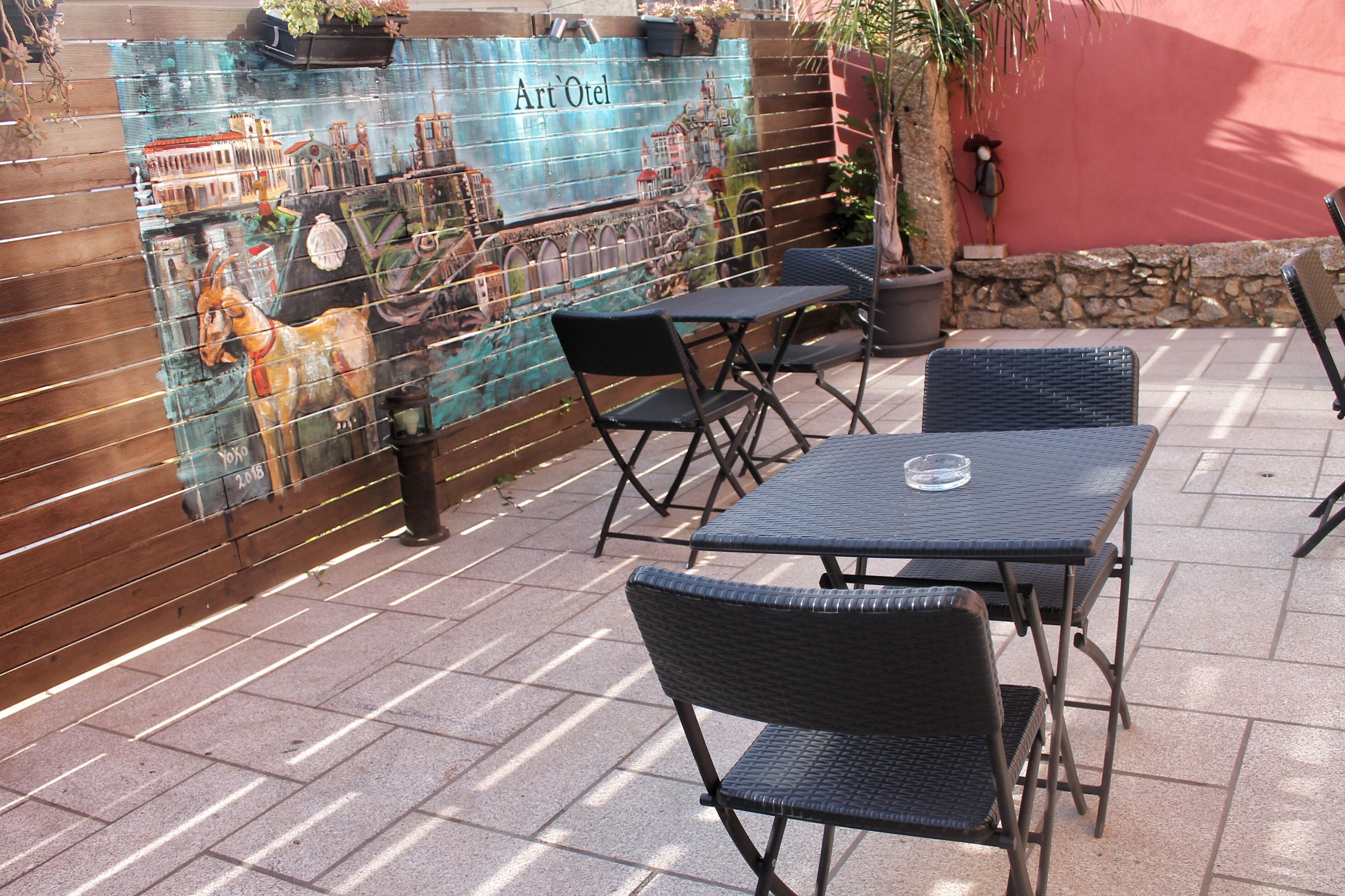 Um pátio externo com um mural, uma mesa e cadeiras.