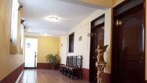 Um corredor com piso de azulejos, uma estátua, uma porta e uma janela.
