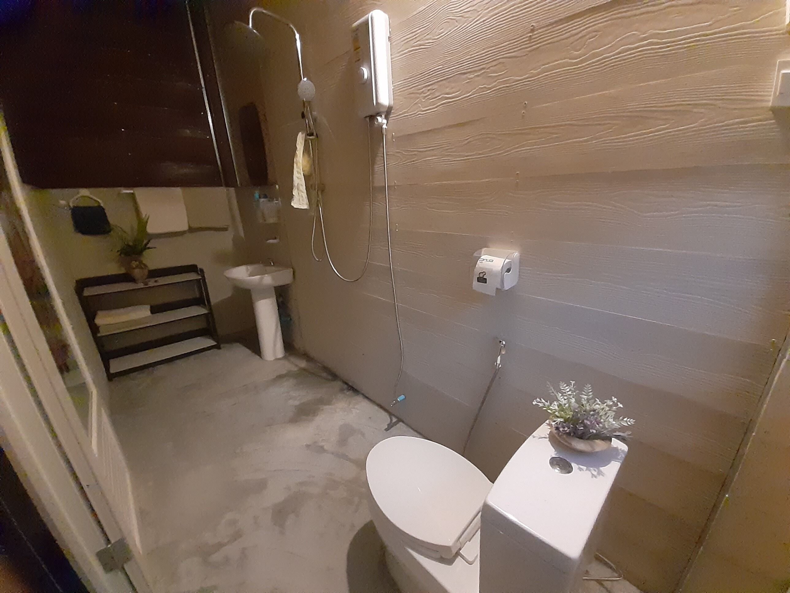 Casa de banho compacta com sanita, lavatório e chuveiro.