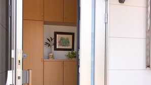 Quarto com porta deslizante, uma pequena mesa com planta em vaso e luminária fixada na parede.