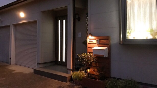 Uma casa moderna com garagem, varanda com banco e um pequeno jardim com plantas.