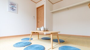 Um quarto com esteiras de tatame, uma mesa de madeira com objetos de cerâmica e um quadro na parede.