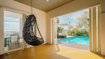 Quarto com cadeira suspensa, piscina e porta de vidro corria para o exterior.