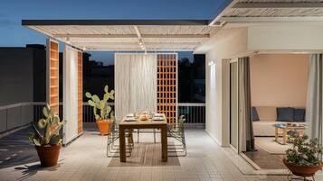 Pátio externo com mesa posta para refeições, rodeado por plantas em vasos e um design arquitetônico moderno.