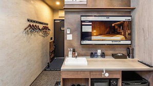 Uma casa de banho moderna com um espelho grande, uma pia e uma televisão mostrando um quarto.