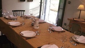 Mesa de jantar posta para uma refeição, com pratos, talheres e copos de vinho.