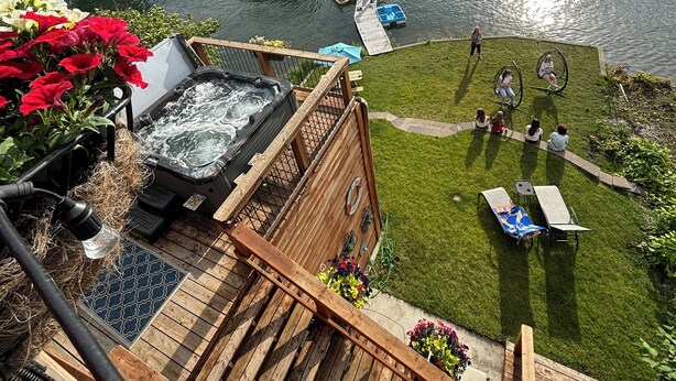 Um deck com hidromassagem, área de estar externa e vista para um lago com barcos.