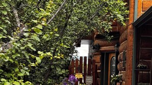 Uma passagem de madeira ladeada por grandes vasos de plantas e um edifício rústico com fachada de madeira.